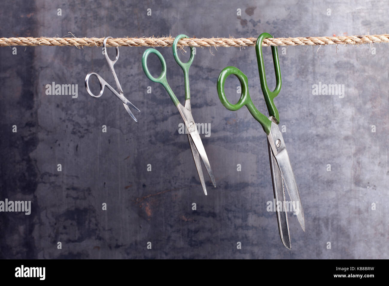 Three scissors hanging on a rope on grunge texture Stock Photo - Alamy