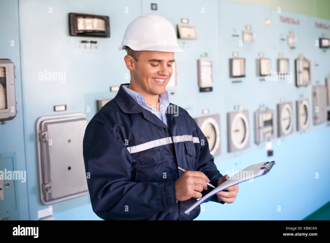 Portrait of young smiling engineer taking notes at control room Stock ...