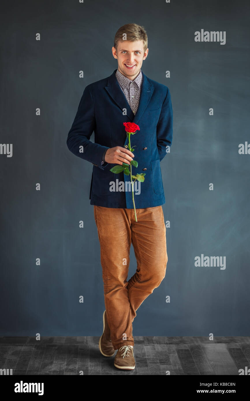 Full length portrait of happy handsome man with red rose standing ...