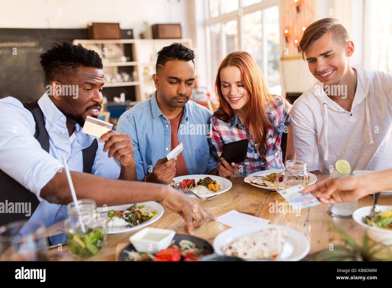 happy friends with money paying bill at restaurant Stock Photo - Alamy