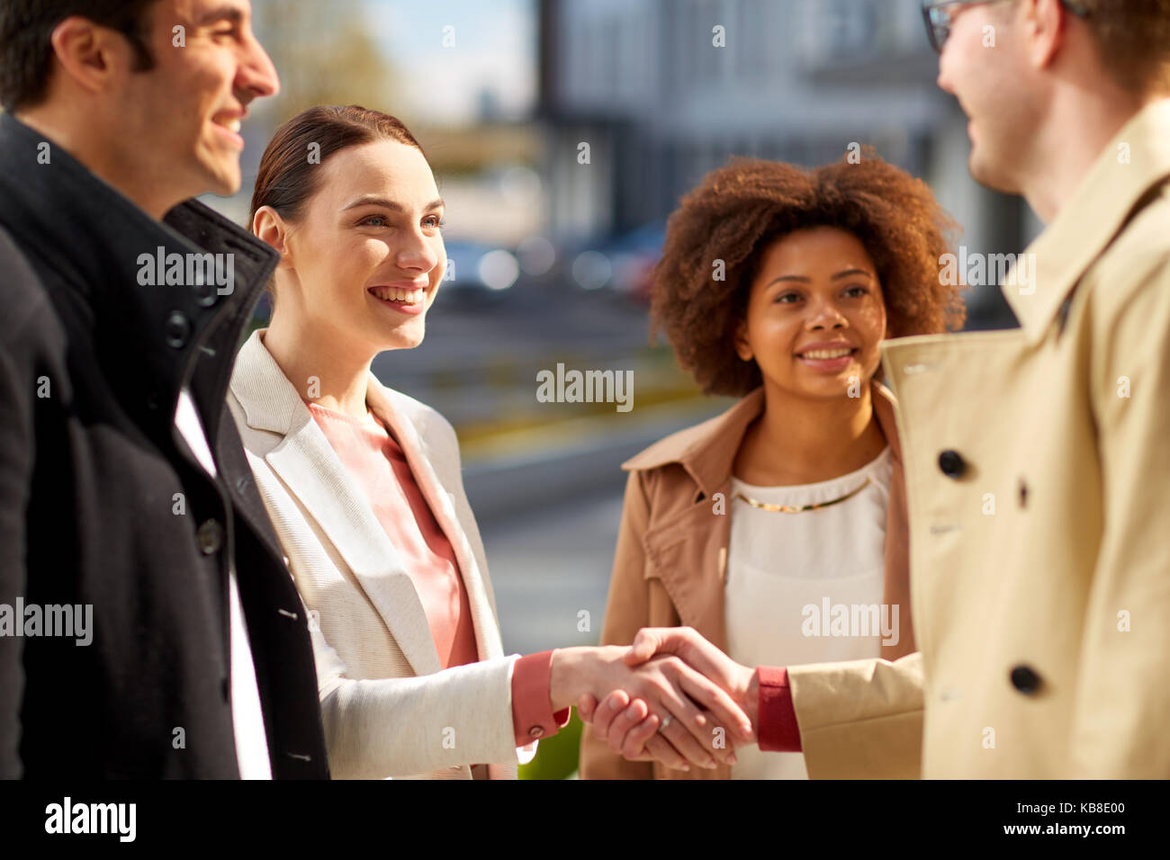 happy people shaking hands on city street Stock Photo - Alamy