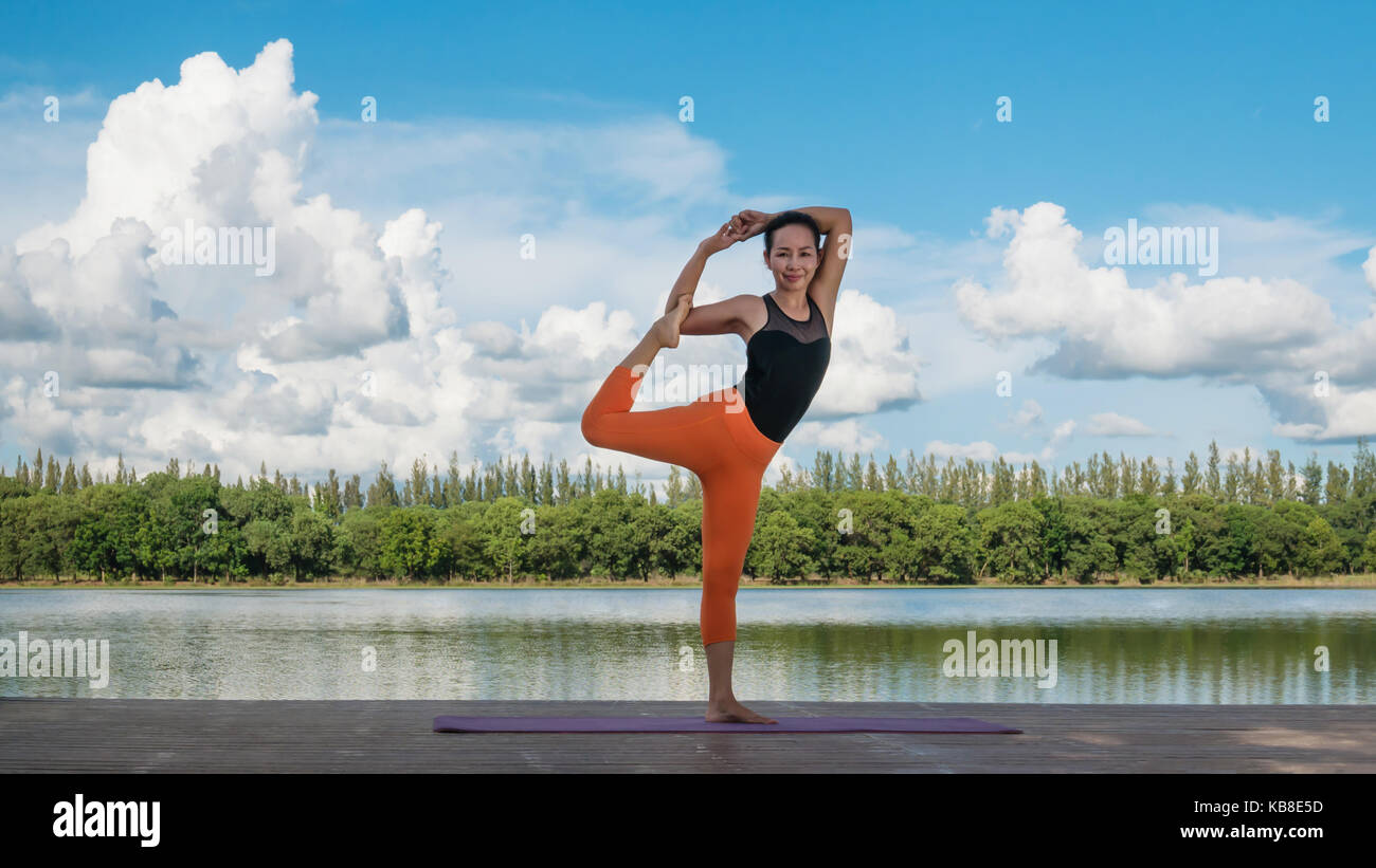 Asian woman practicing yoga pose , exercise outdoors with view of ...