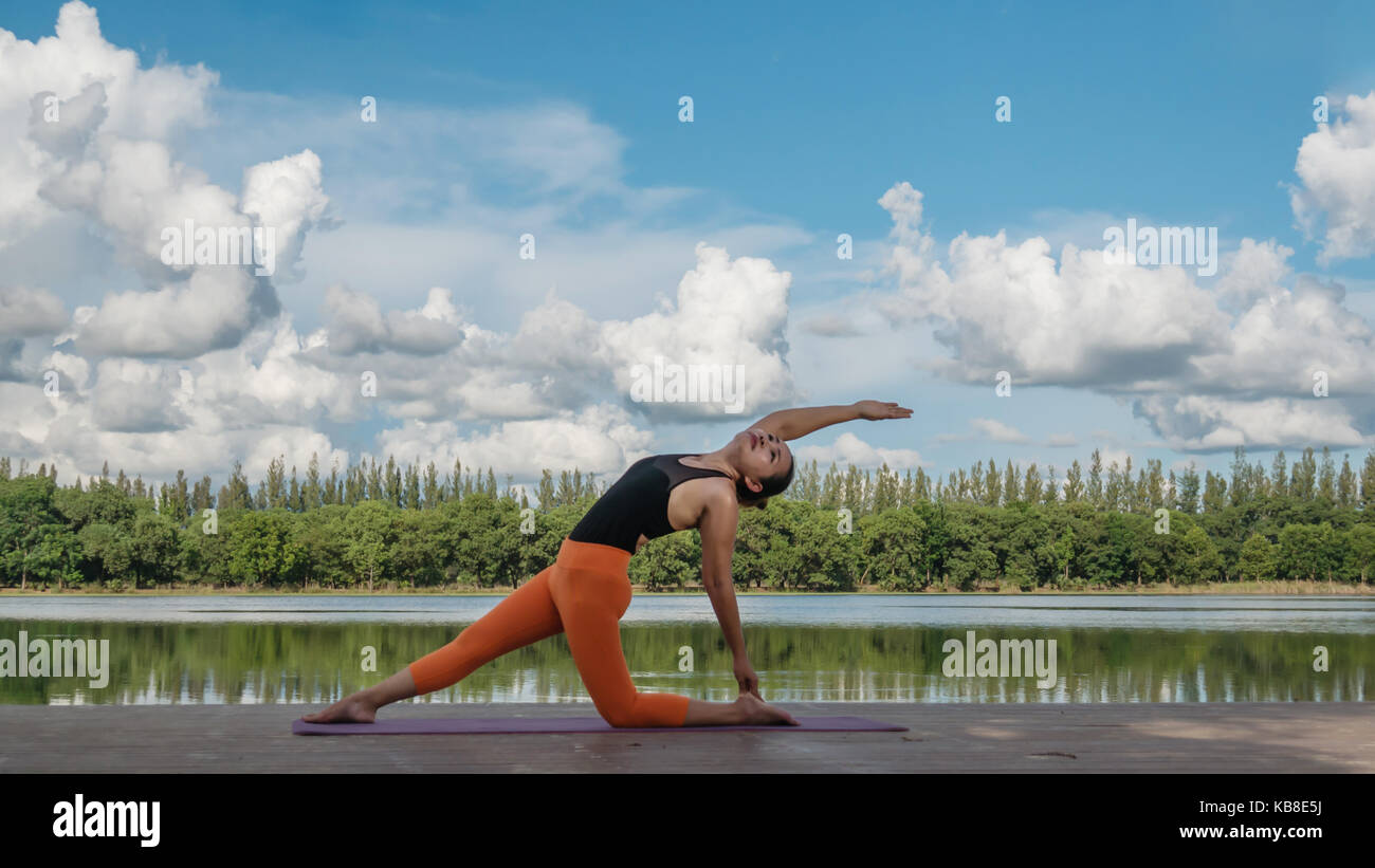 Asian woman practicing yoga pose , exercise outdoors with view of ...