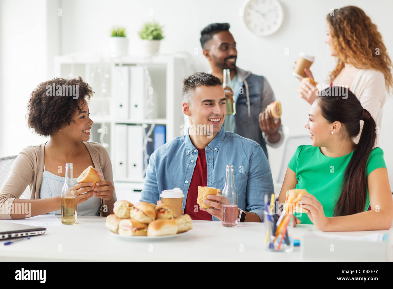 happy friends or team eating at office party Stock Photo - Alamy
