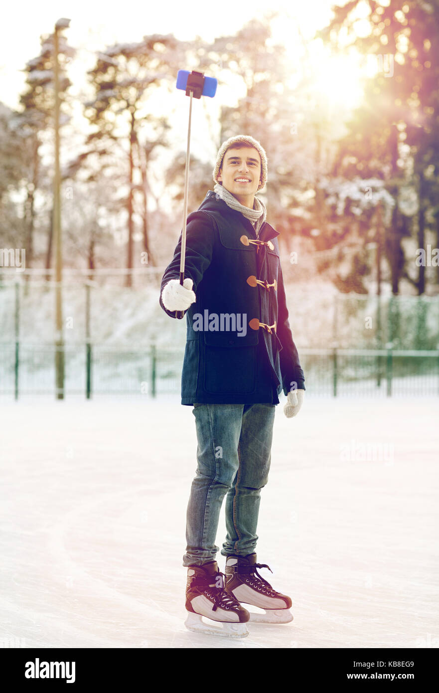 happy young man with smartphone on ice rink Stock Photo - Alamy