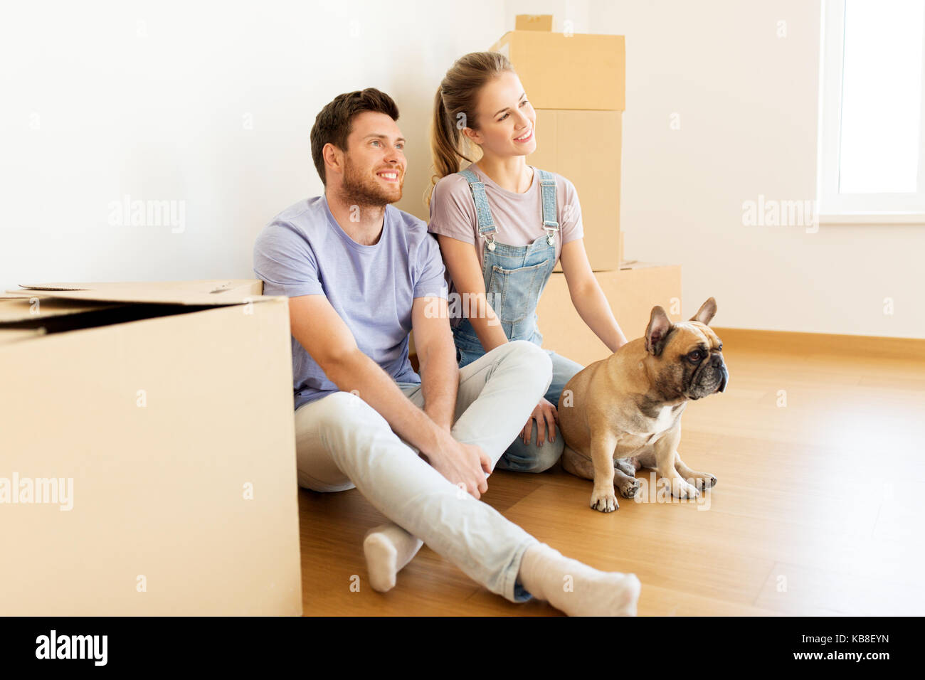 happy couple with boxes and dog moving to new home Stock Photo - Alamy