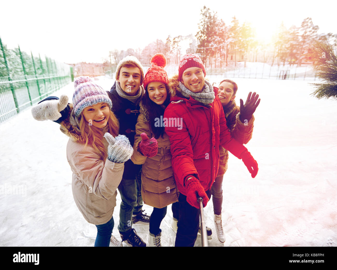 happy friends with smartphone on ice skating rink Stock Photo - Alamy