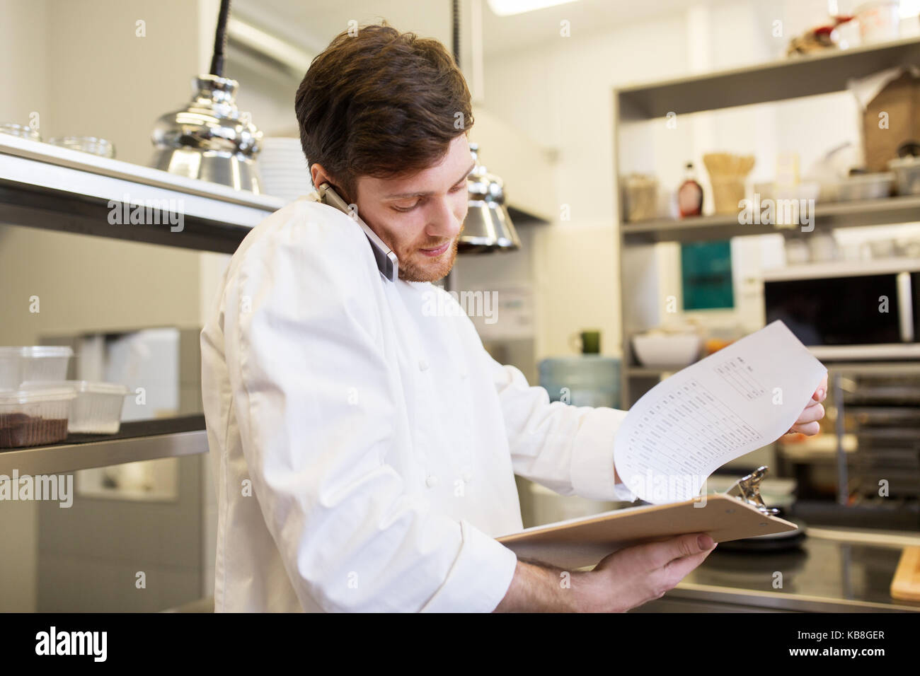 chef cook calling on smartphone at restaurant kitchen Stock Photo - Alamy
