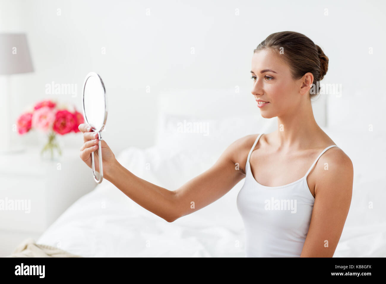 beautiful woman with mirror sitting on bed at home Stock Photo - Alamy