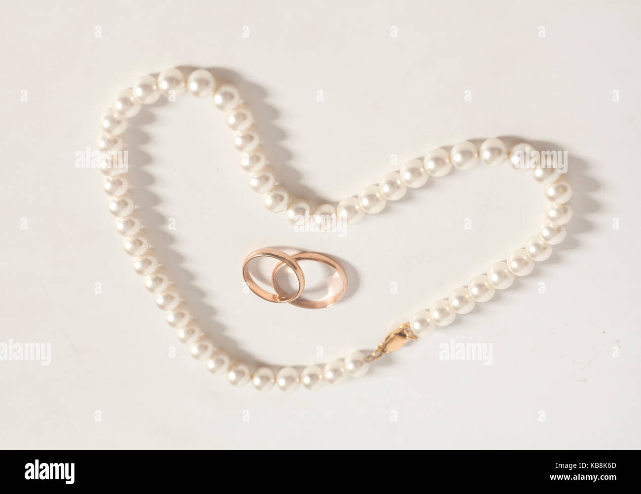 Pearl necklace in heart shape end wedding rings Stock Photo - Alamy
