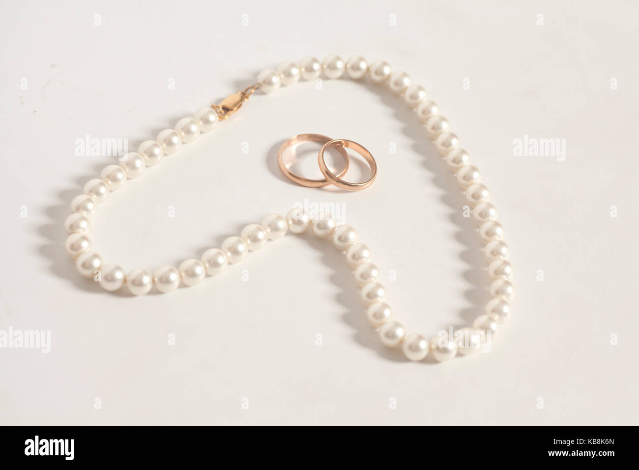 Pearl necklace in heart shape end wedding rings Stock Photo - Alamy