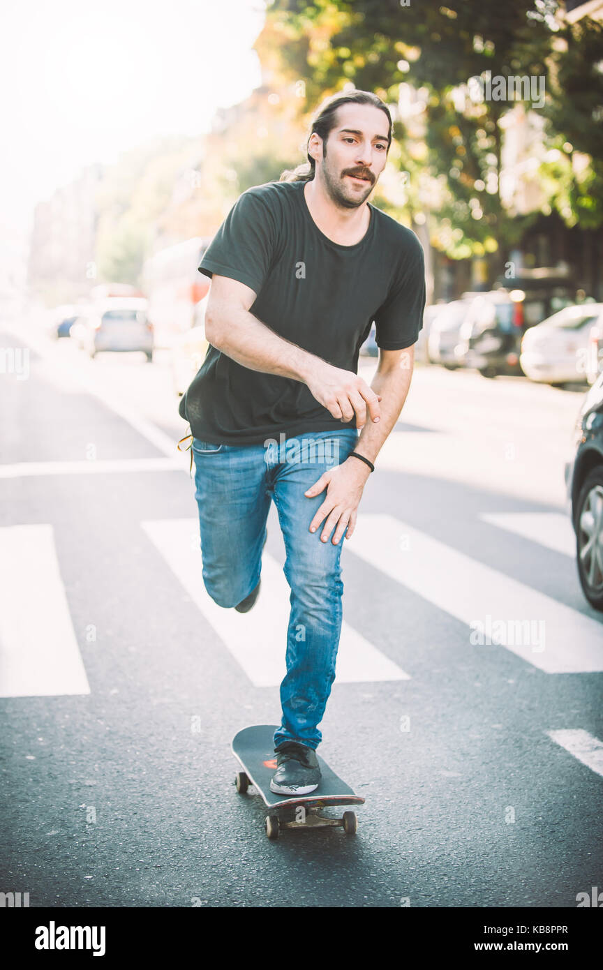 Pro skate rider ride skateboard in front of the car on the city road ...