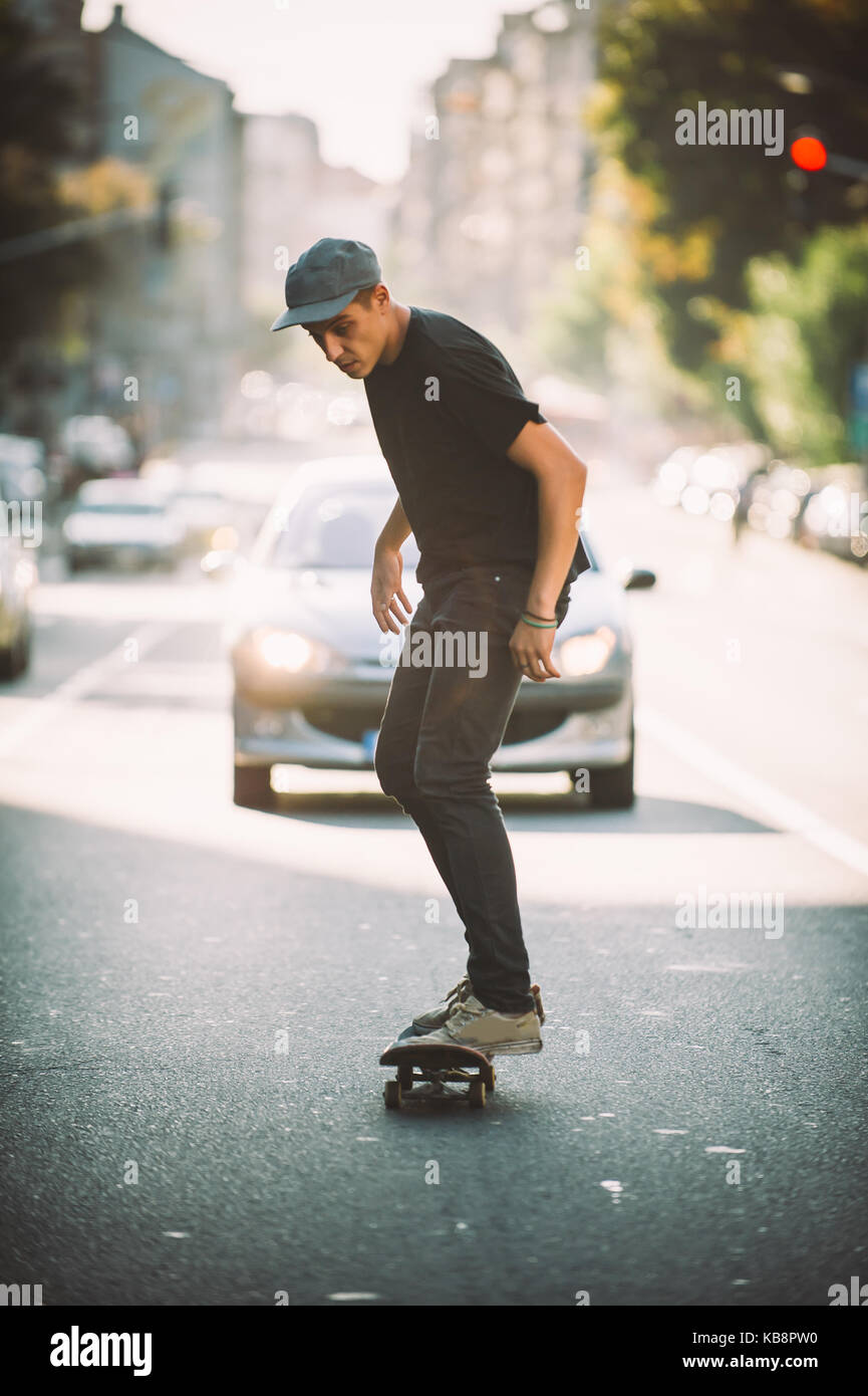 Pro skate rider ride skateboard in front of the car on the city road ...