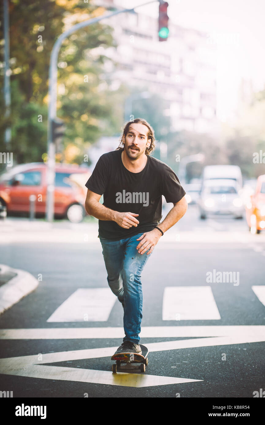 Pro skate rider ride skateboard in front of the car on the city road ...