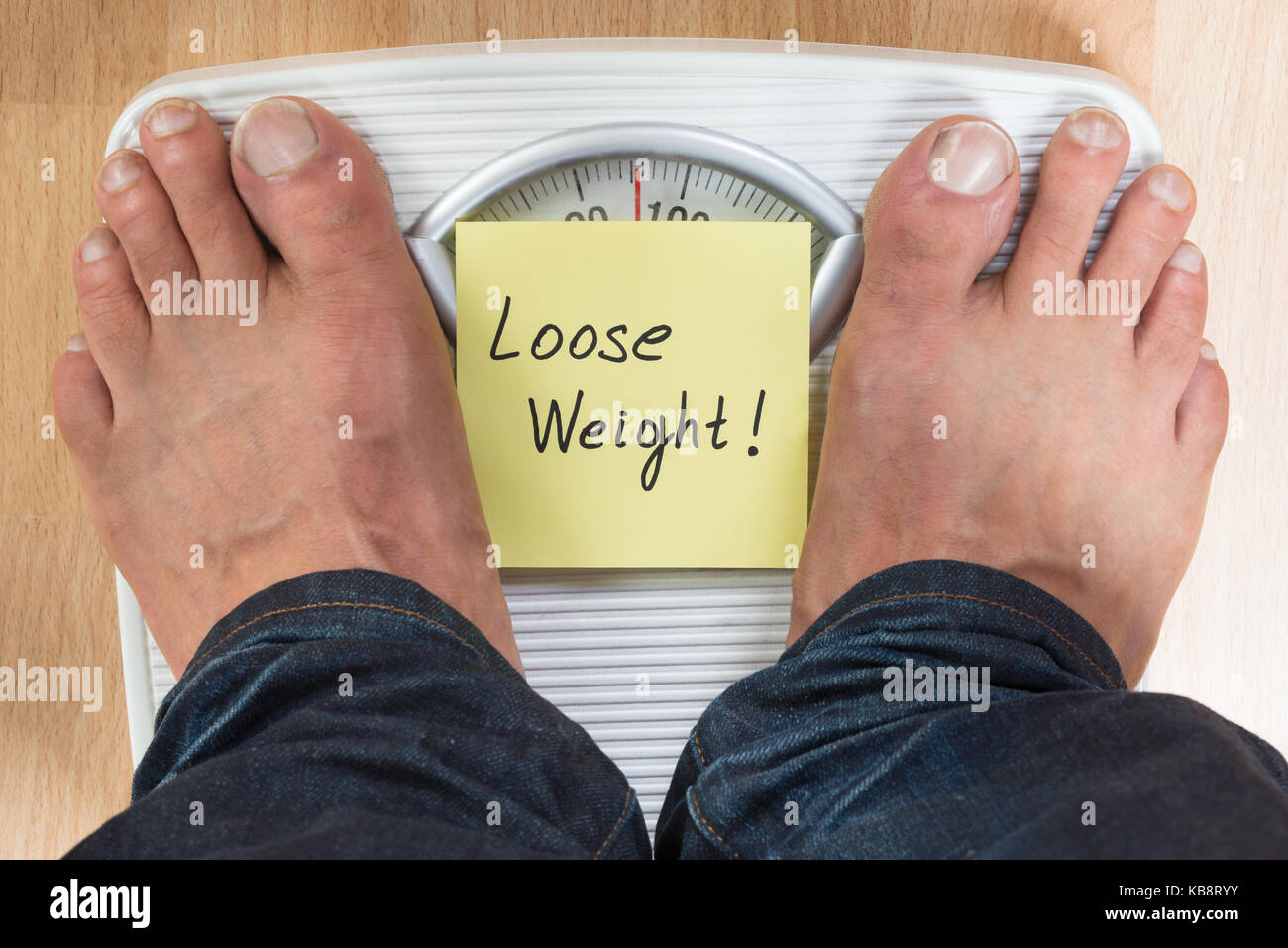 Low section of man standing on scale with loose weight sign Stock Photo ...