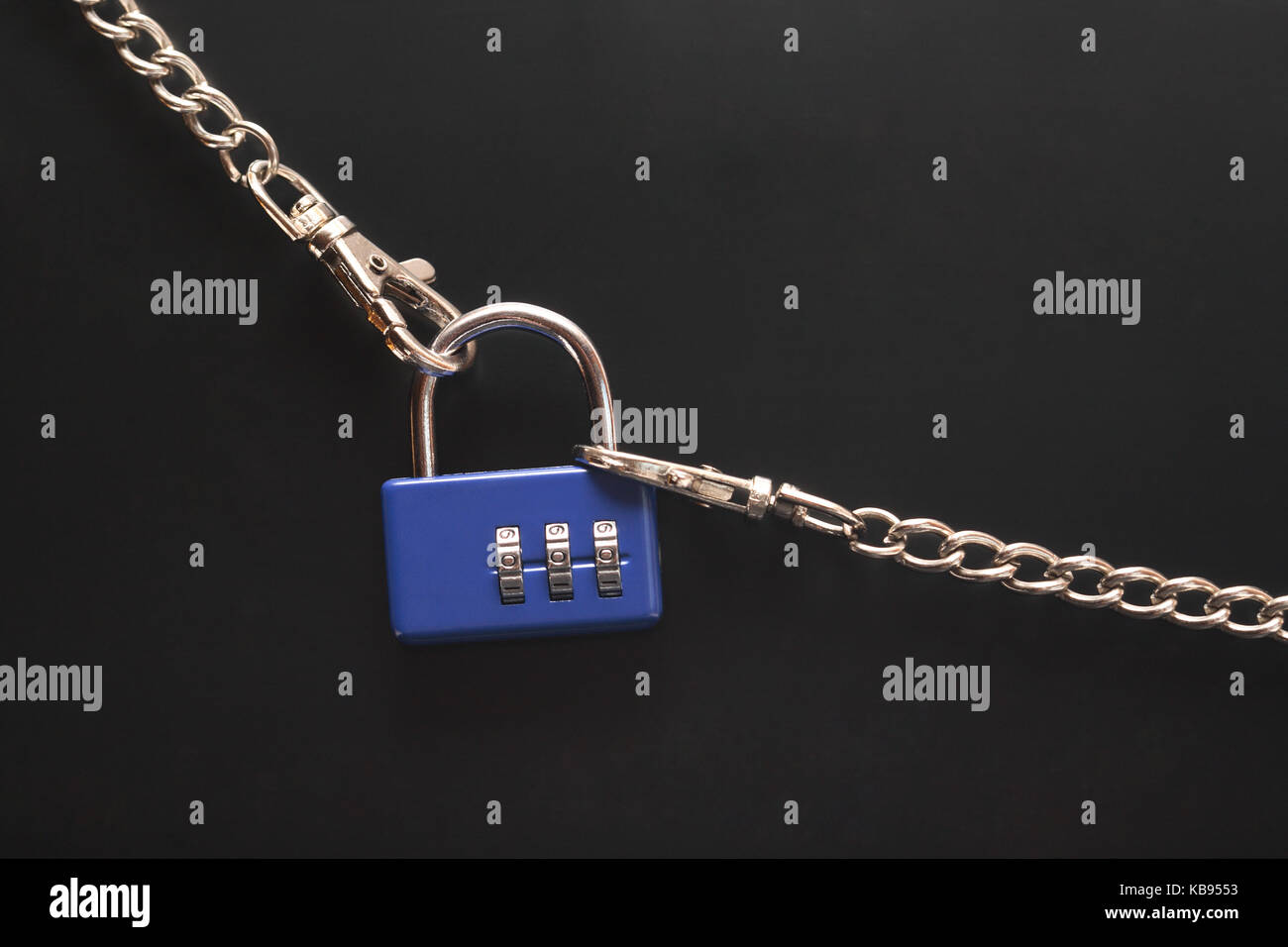 Blue combination padlock hanging on black background with metal chains ...