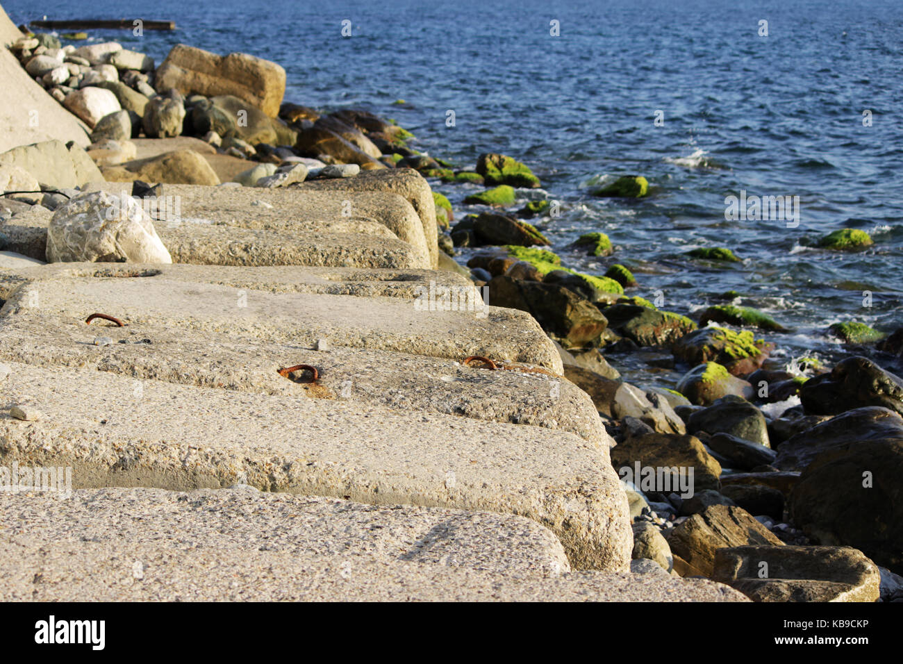 Large concrete rectangular blocks to protect the shore from erosion lie ...