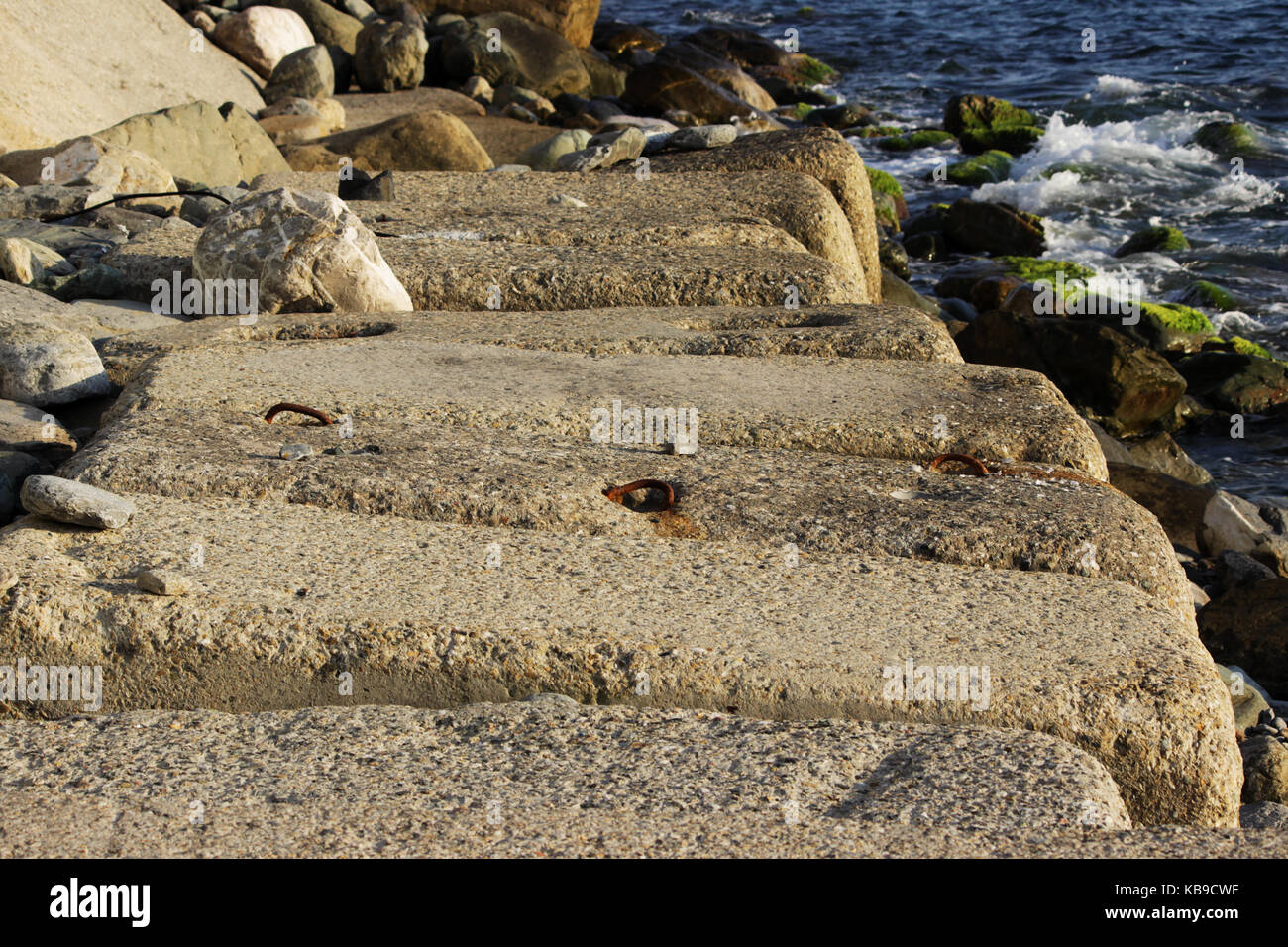 Large concrete rectangular blocks to protect the shore from erosion lie ...