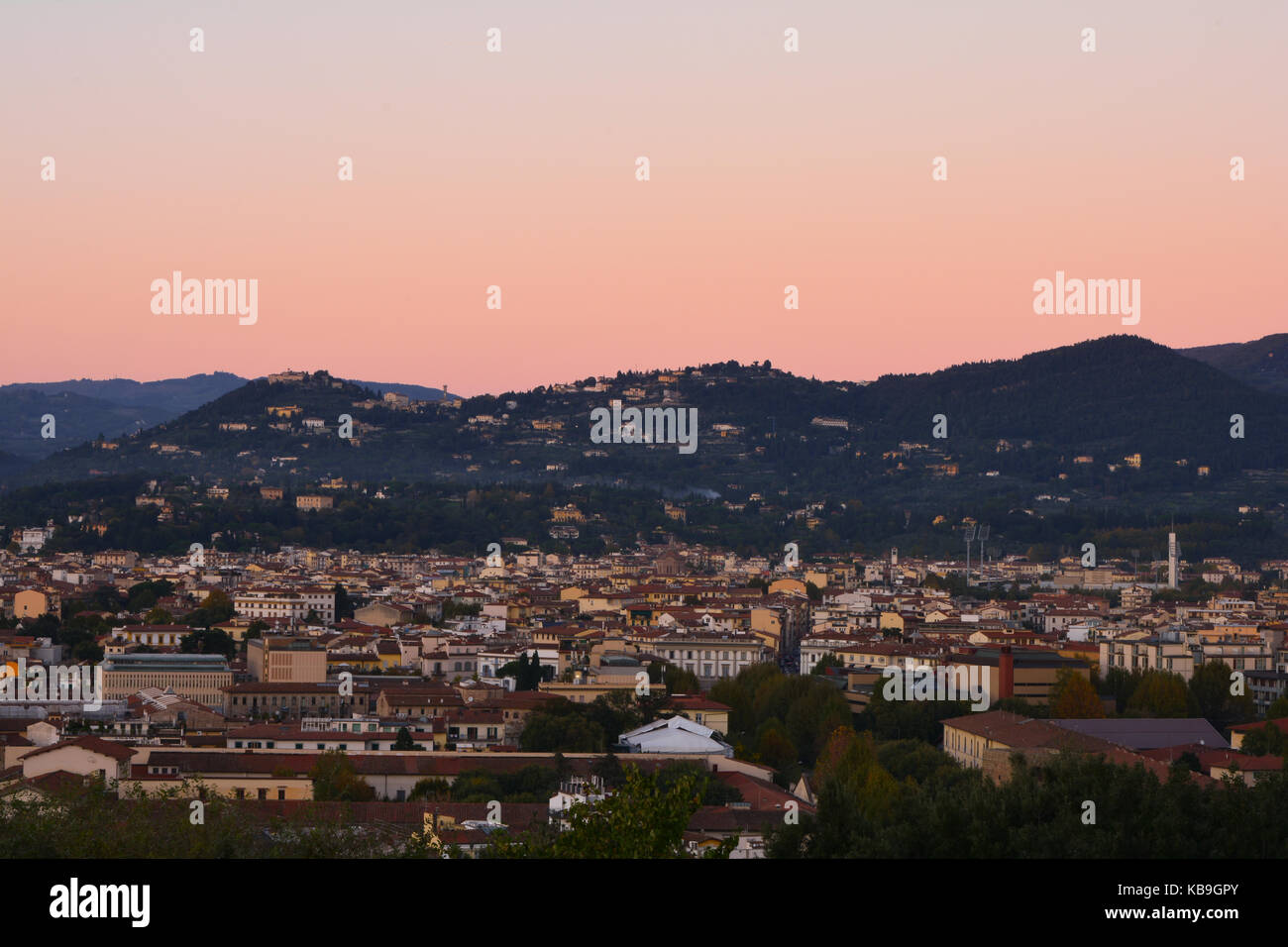 A pink sky dominates over city of Florence during sunset with hills in ...