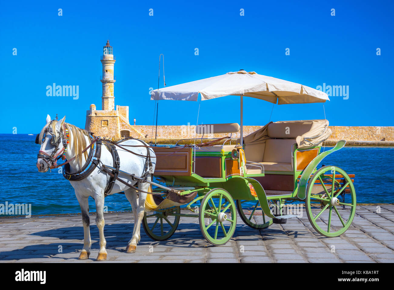 View of the old harbor of Chania with horse carriages and lighthouse ...
