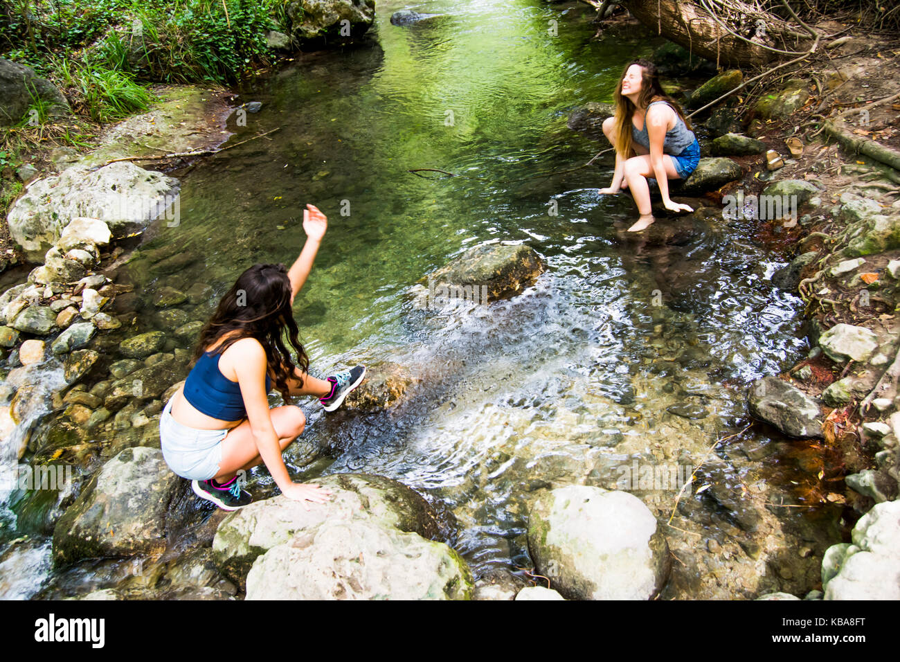 Two beautiful women in nature, splashing water in a river of a mountain ...