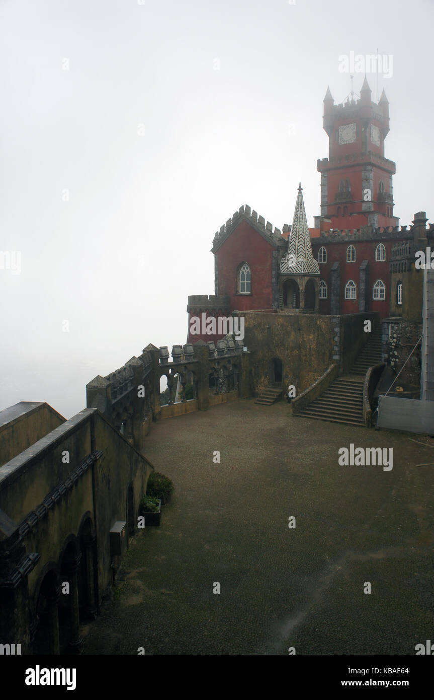 Red tower and patio of Da Pena palace during foggy, rainy weather ...