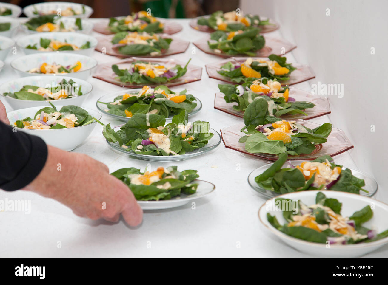 plates of spinach salad lined up on a table at a reception or party ...