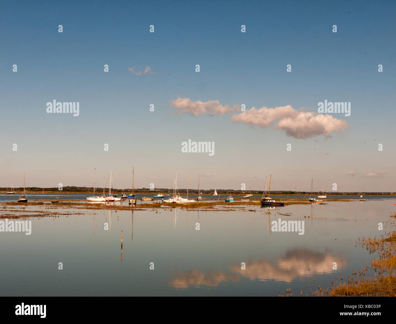 beautiful estuary scene with blue sky moored boats, masts, and ...