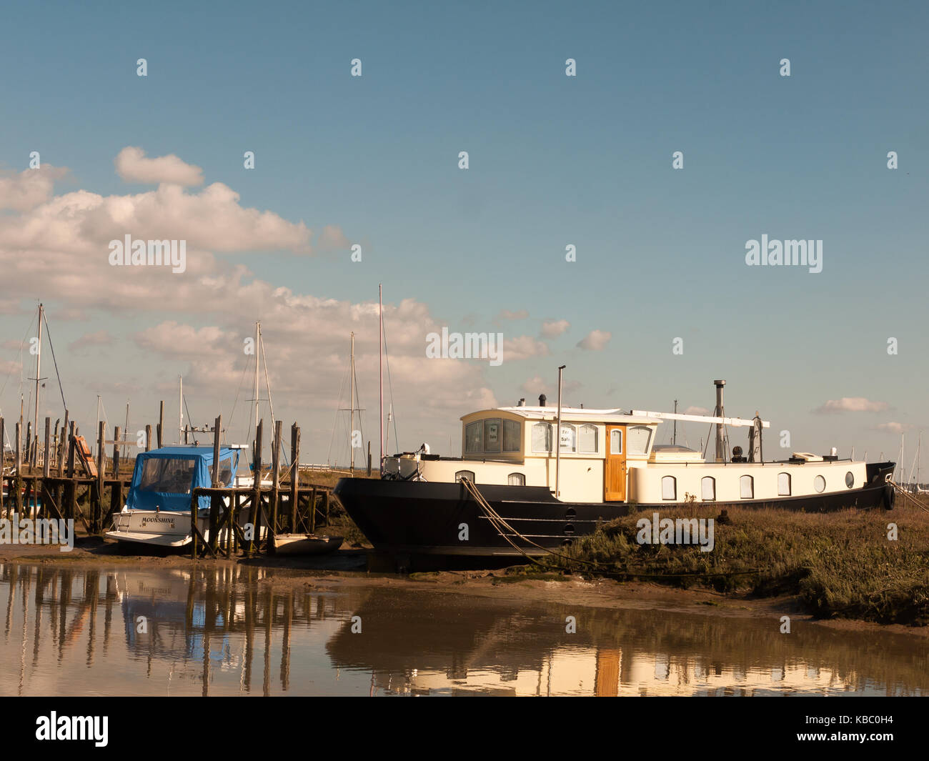 parked moored white and black boat in dockland marshland; essex ...
