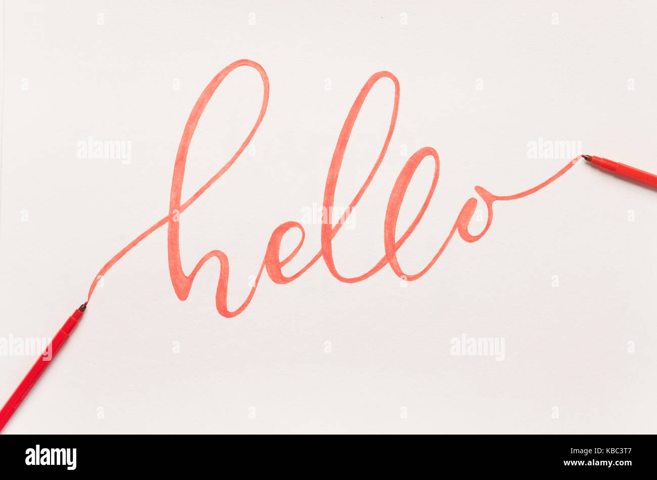 Greeting phrase 'Hello' handwritten with orange marker on white paper ...