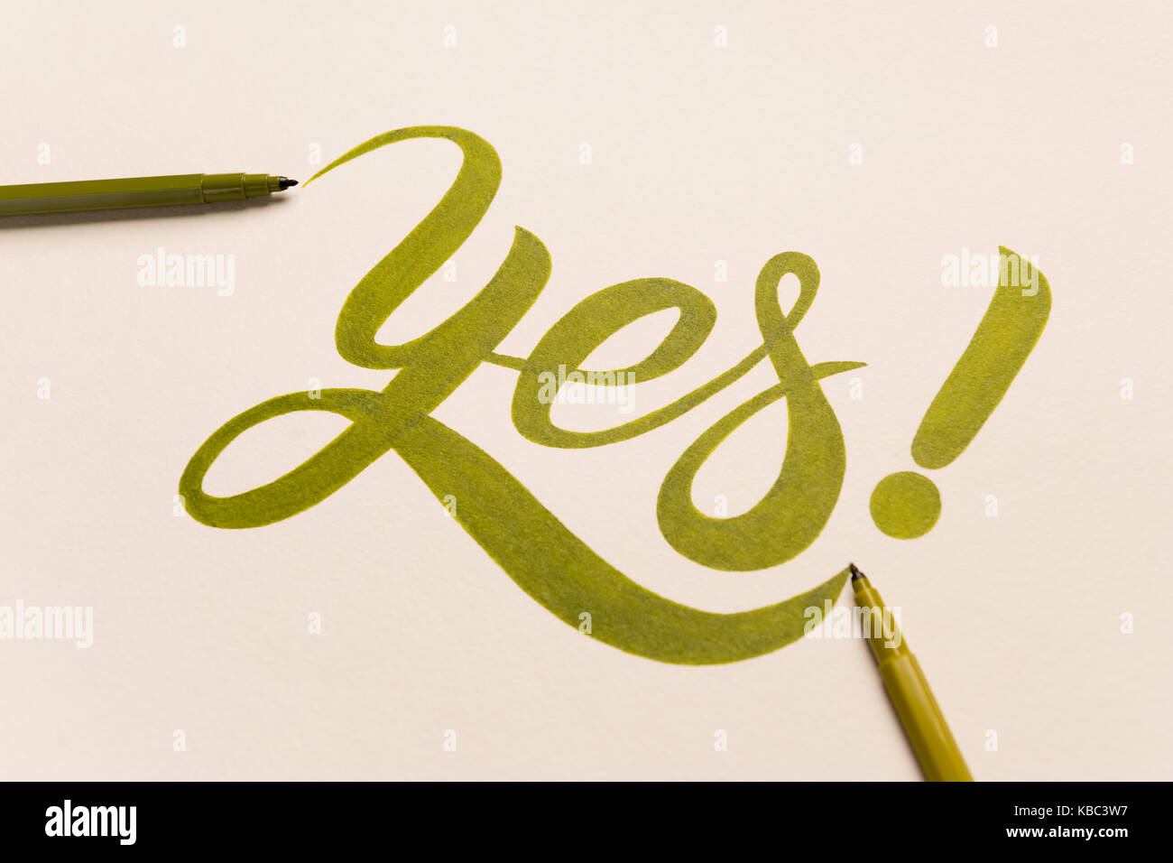 Green hand drawing phrase YES on white sheet with colorful green ...