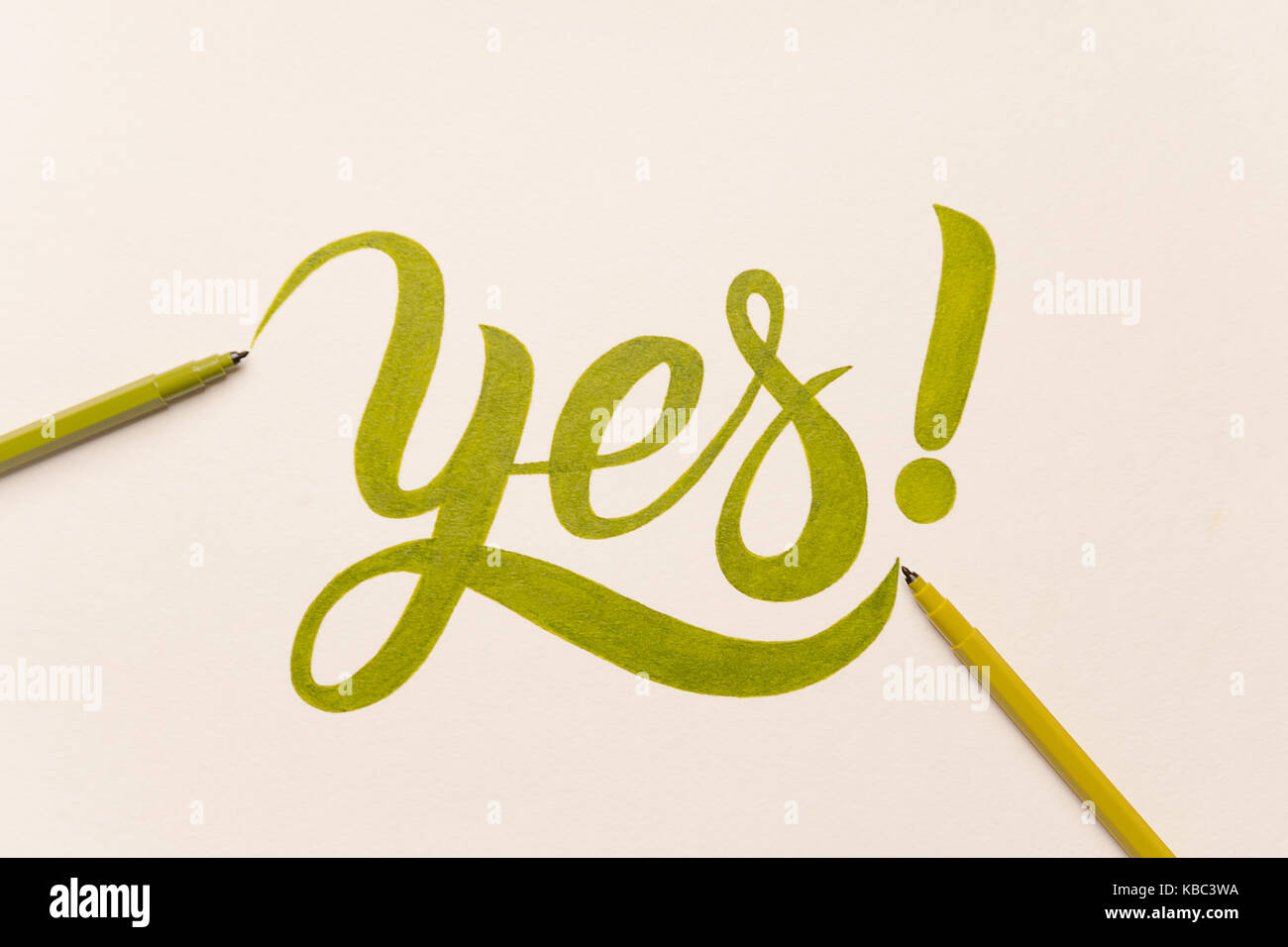 Green hand drawing phrase YES on white sheet with colorful green ...