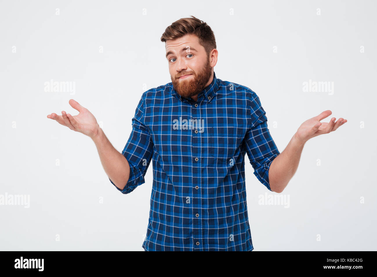 Confused young bearded man standing and shrugging shoulders isolated ...