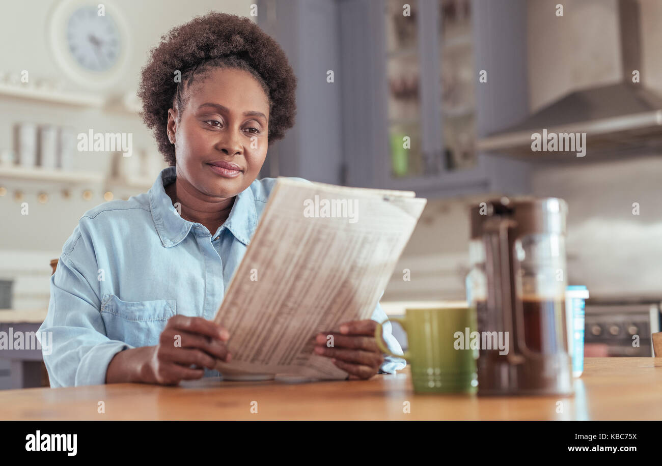 Young woman drinking coffee and reading the newspaper at home Stock ...