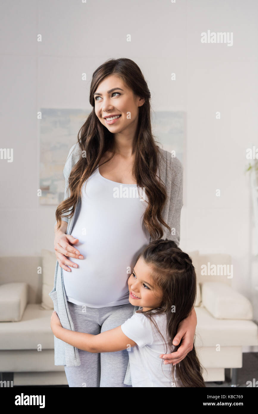 Girl hugging pregnant mother Stock Photo - Alamy
