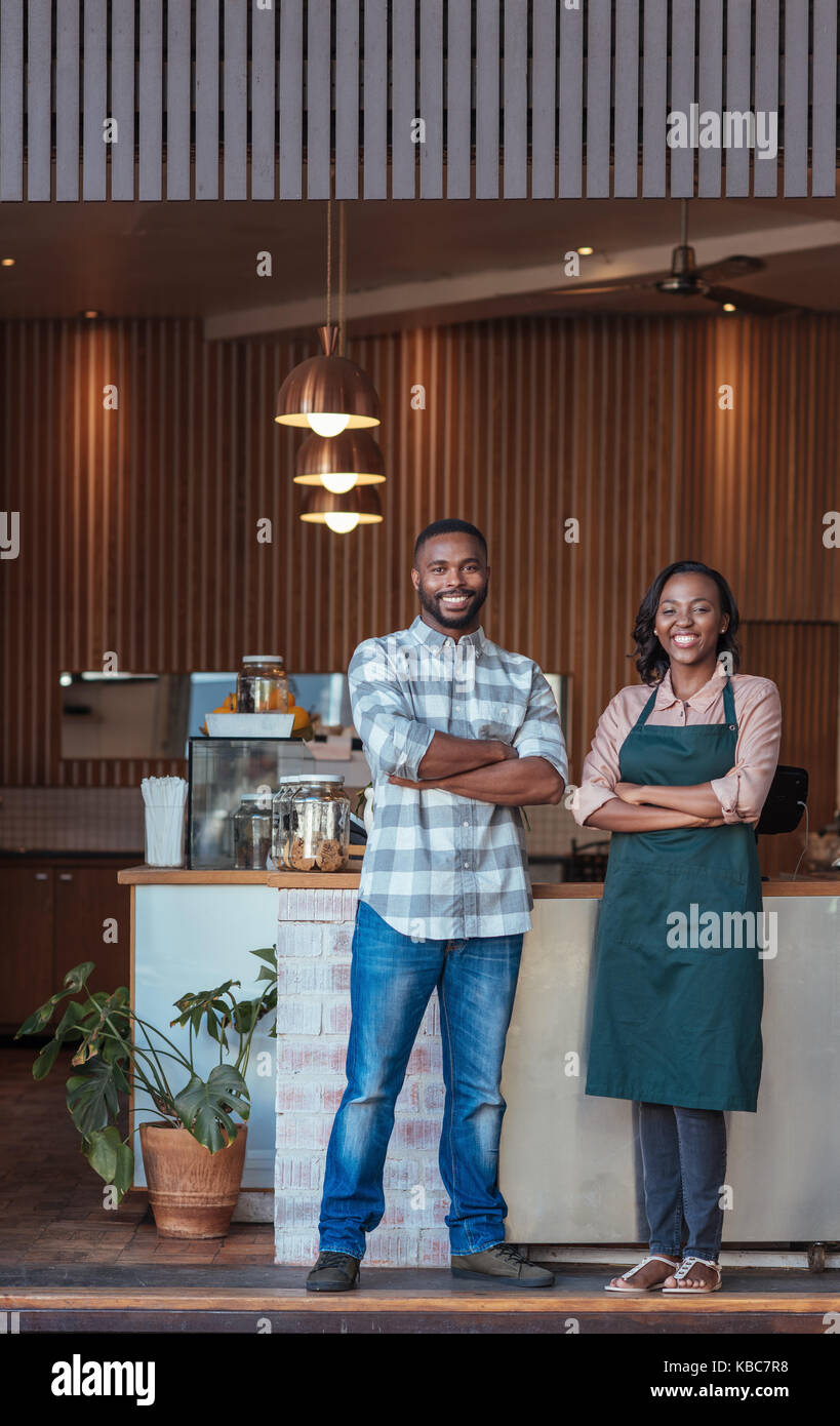 Smiling African entrepreneurs standing at the counter of their cafe ...