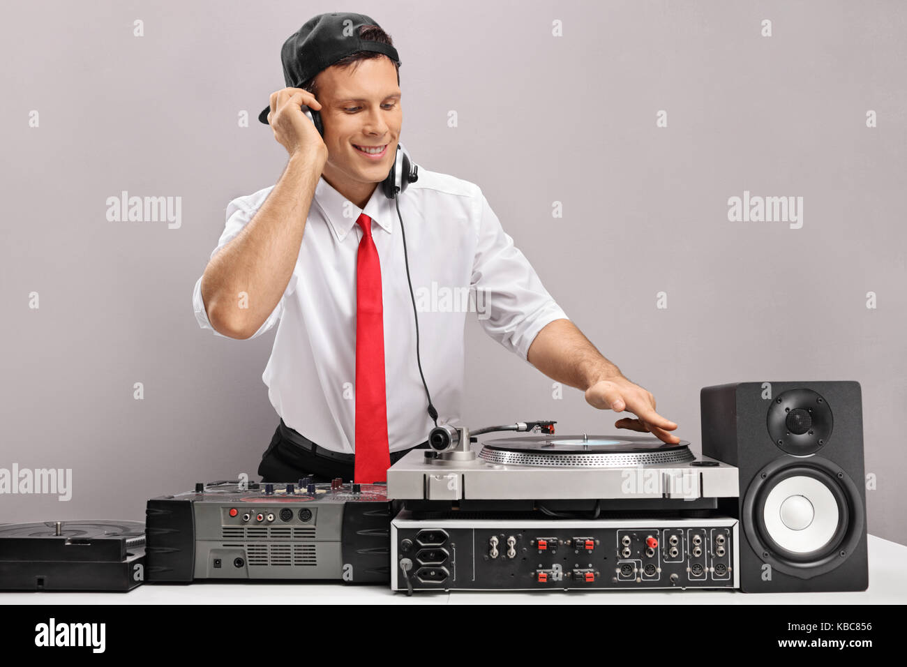 Formally dressed guy playing music on a turntable isolated on gray ...
