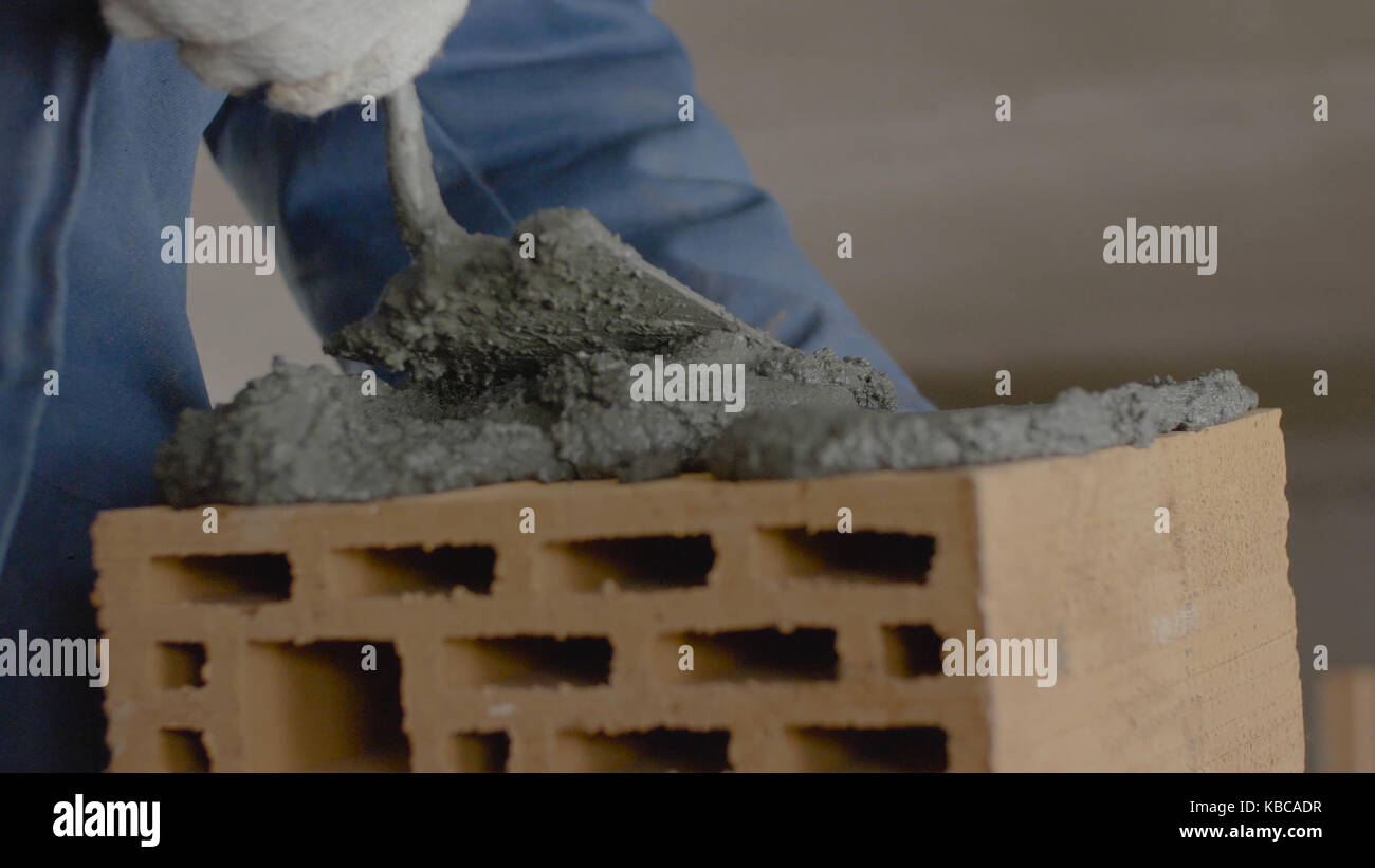 Construction of brick wall. Trowel spreading cement on bricks. Worker ...