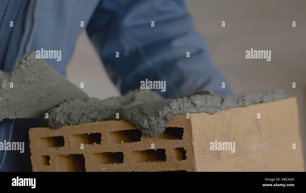 Construction of brick wall. Trowel spreading cement on bricks. Worker ...