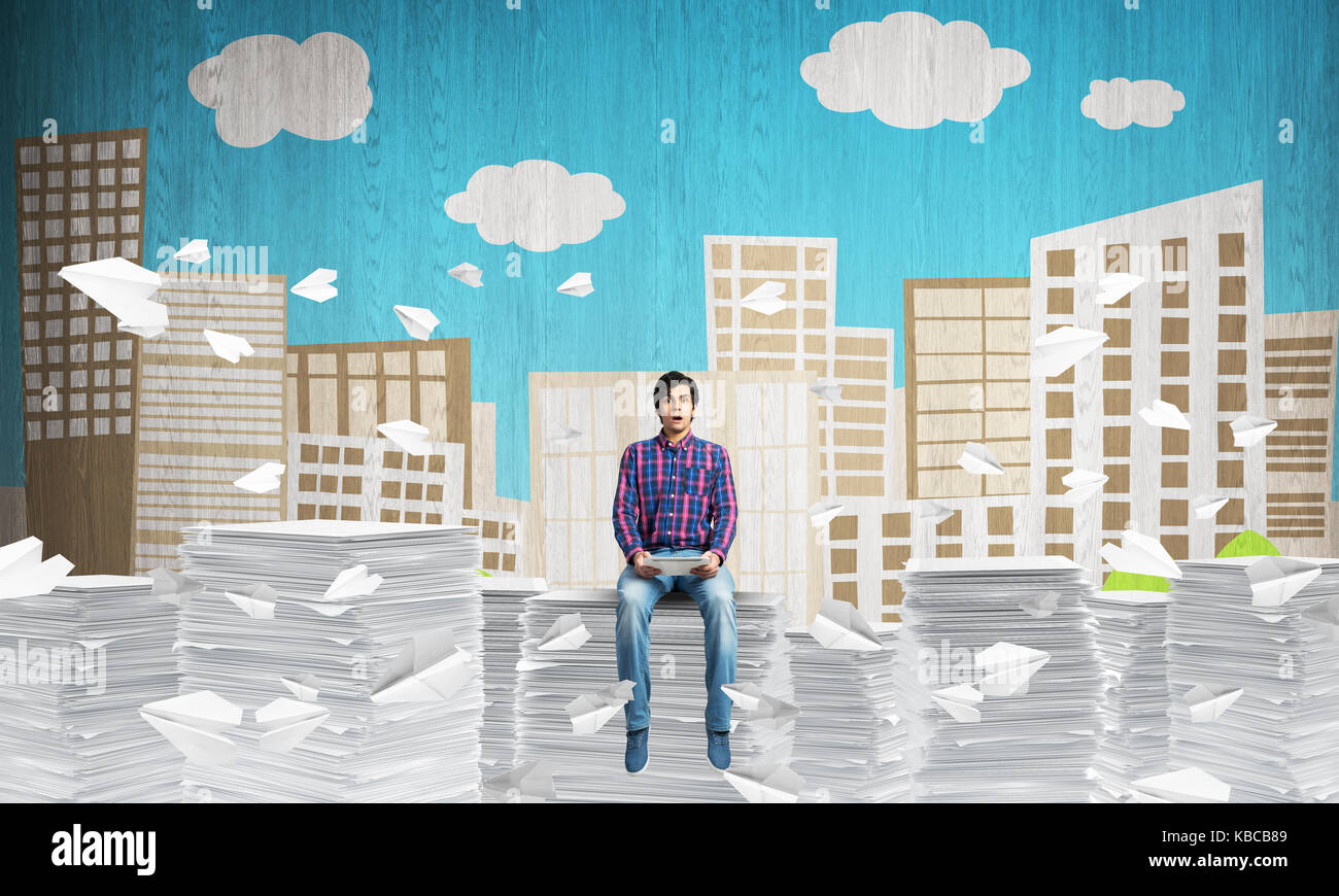 Young man sitting on pile of paper documents Stock Photo - Alamy
