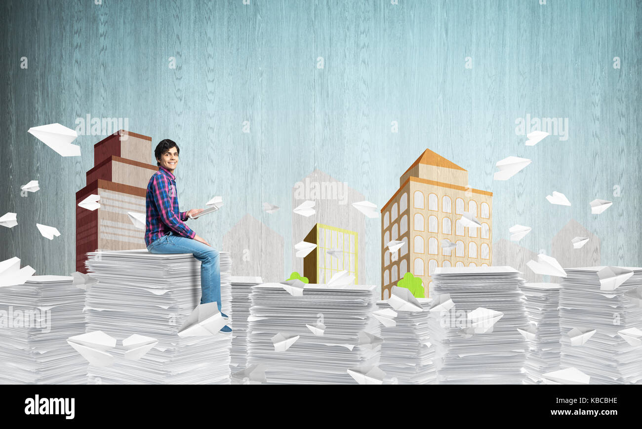 Young man sitting on pile of paper documents Stock Photo - Alamy