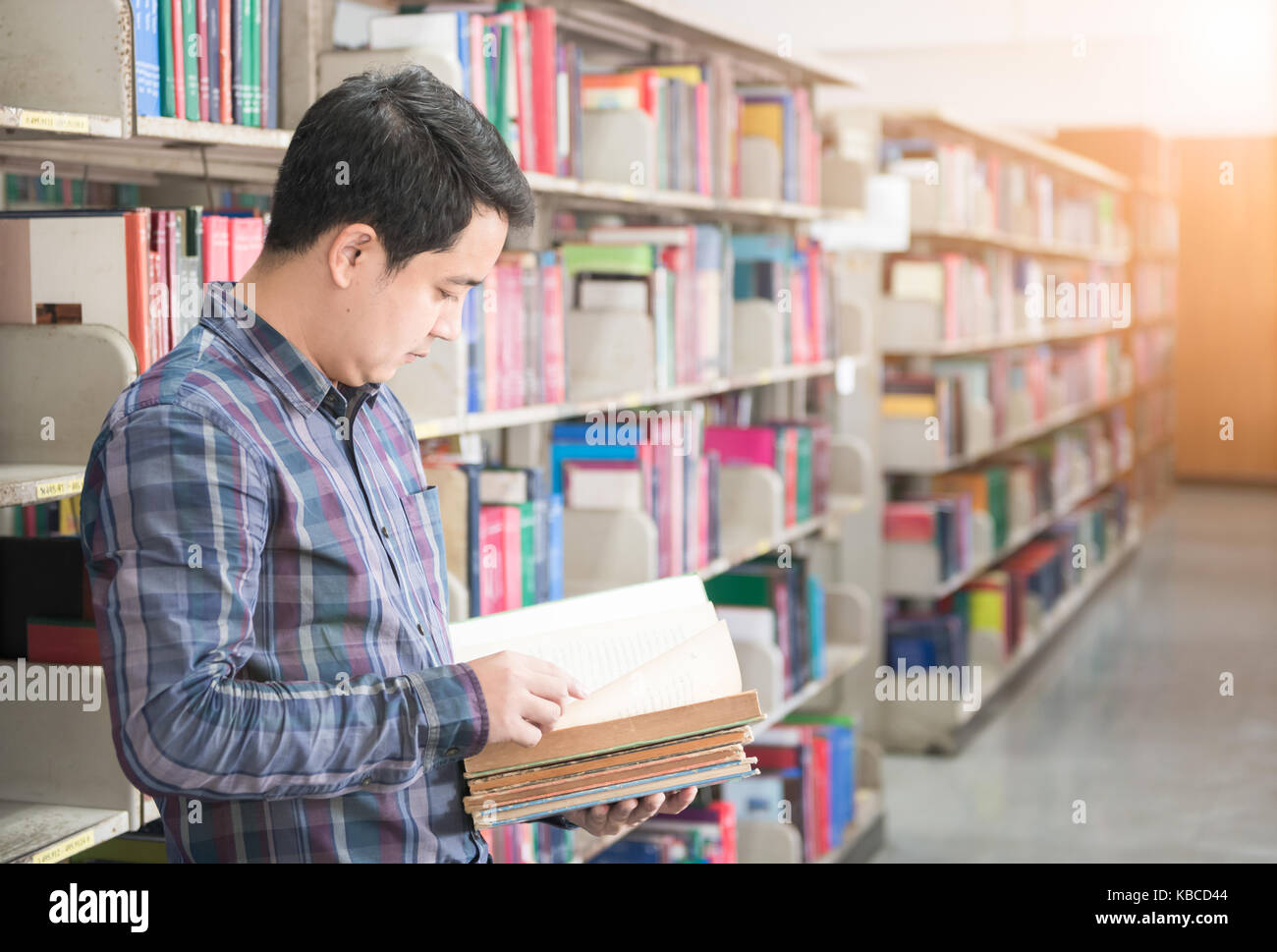 asian male student reading a book in a library, knowledge, education ...
