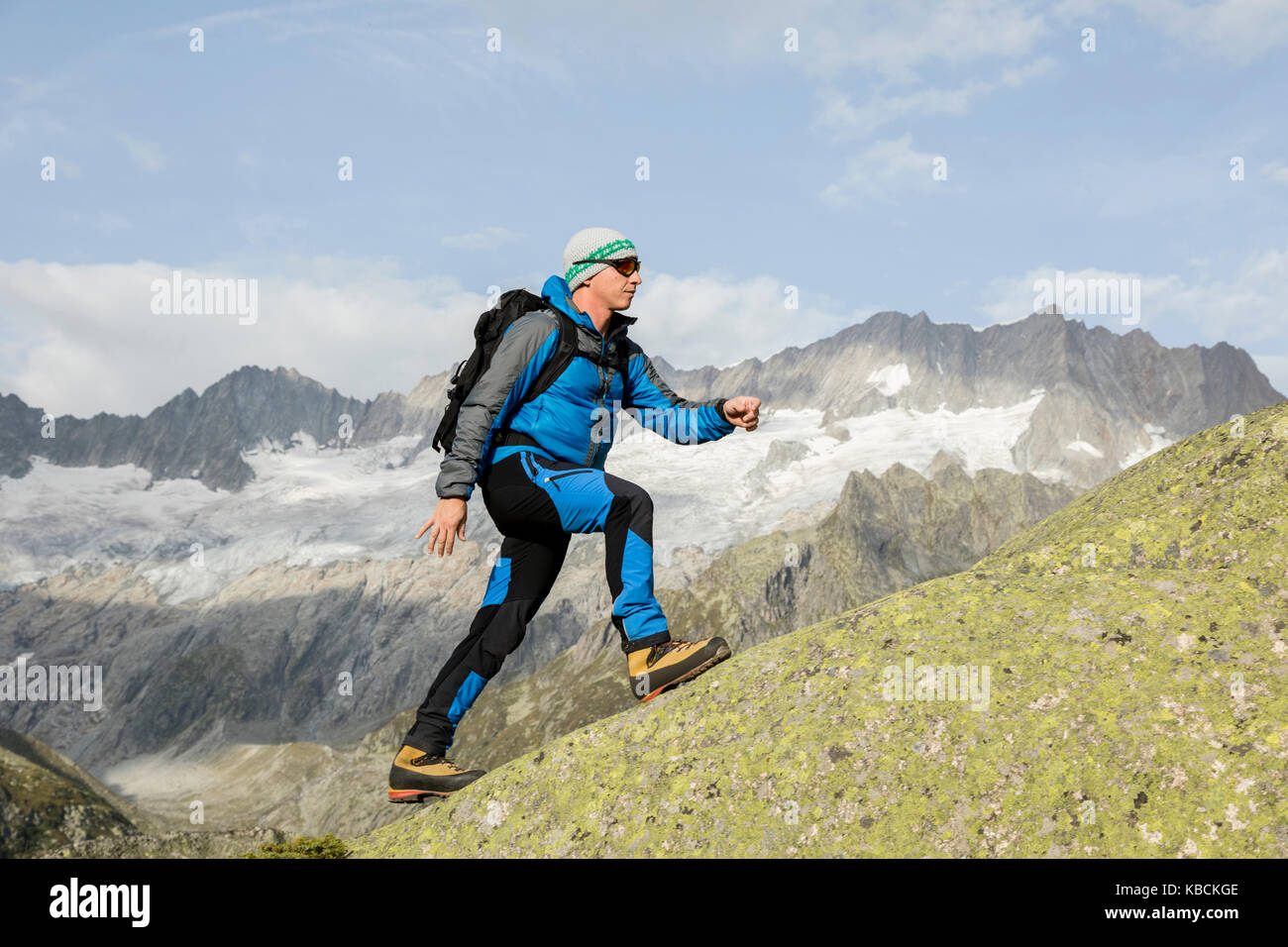 A sporty alpinist climbs a mountain summit in the Swiss Alps Stock ...