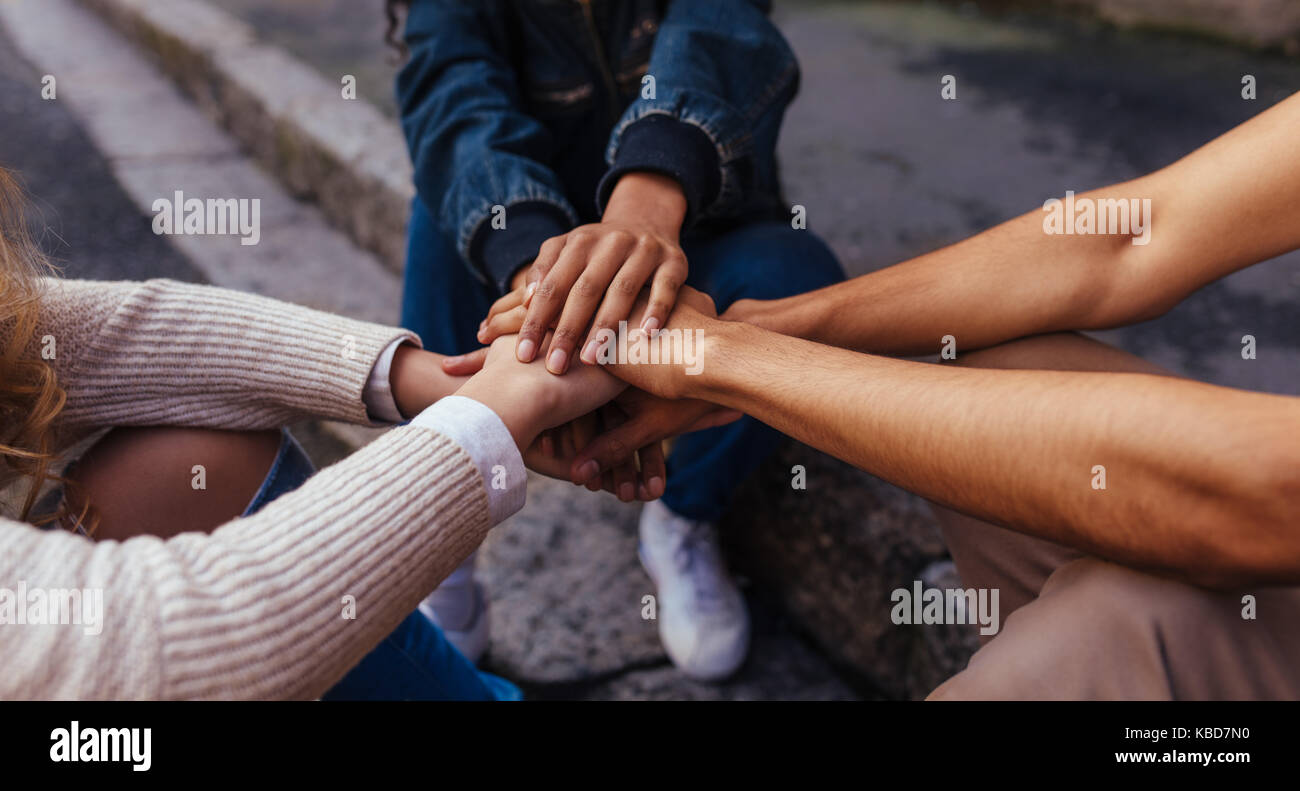 Unity and teamwork. Closeup image of young students making a stack of ...