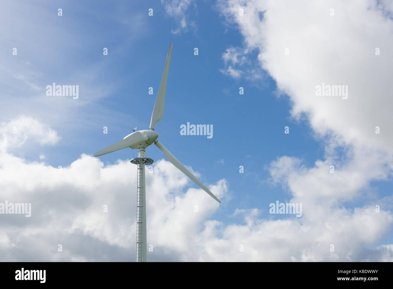 Wind turbine set against a blue sky and white fluffy clouds with ...