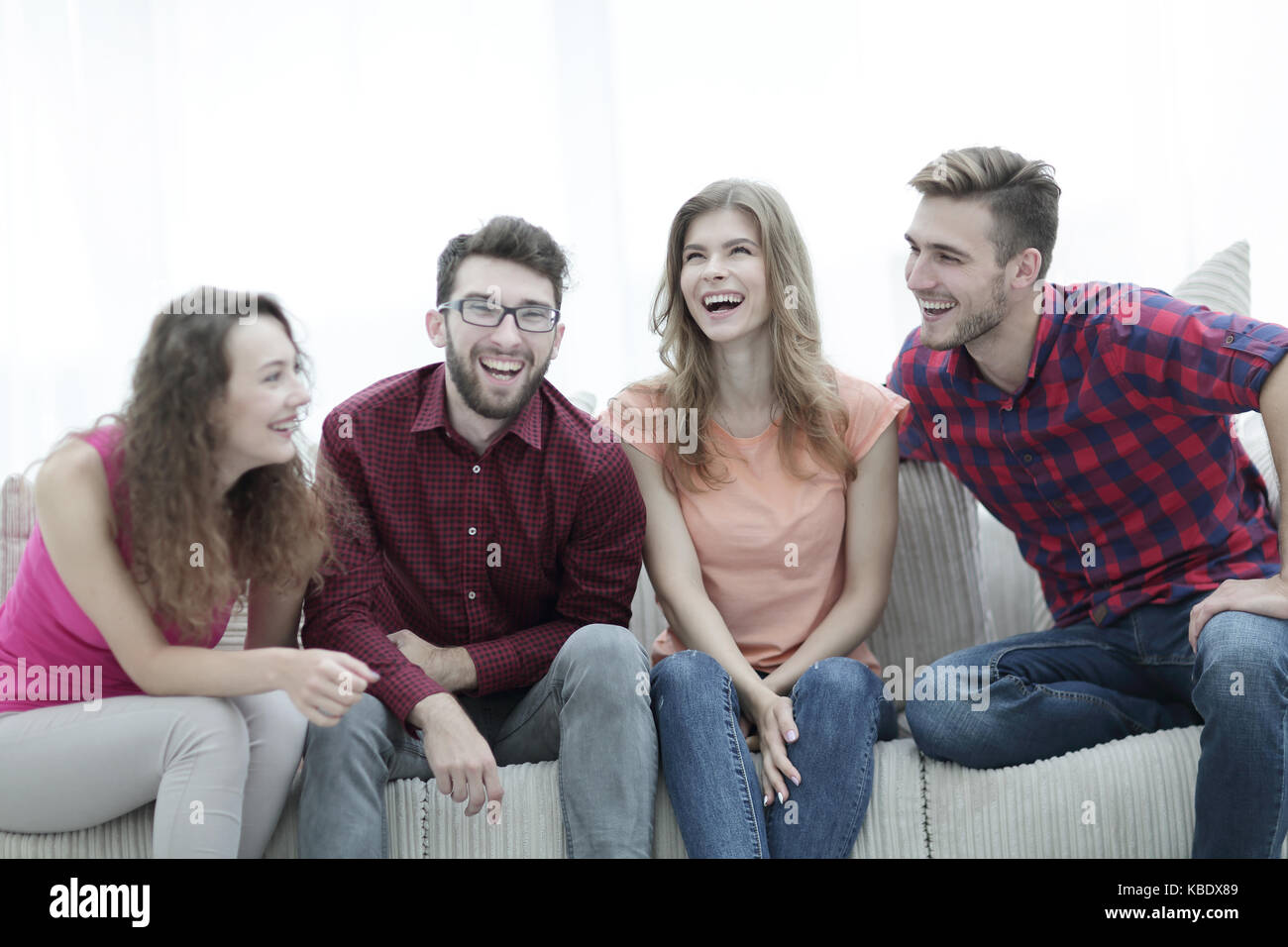 group of cheerful young people sitting on the couch in the living room ...