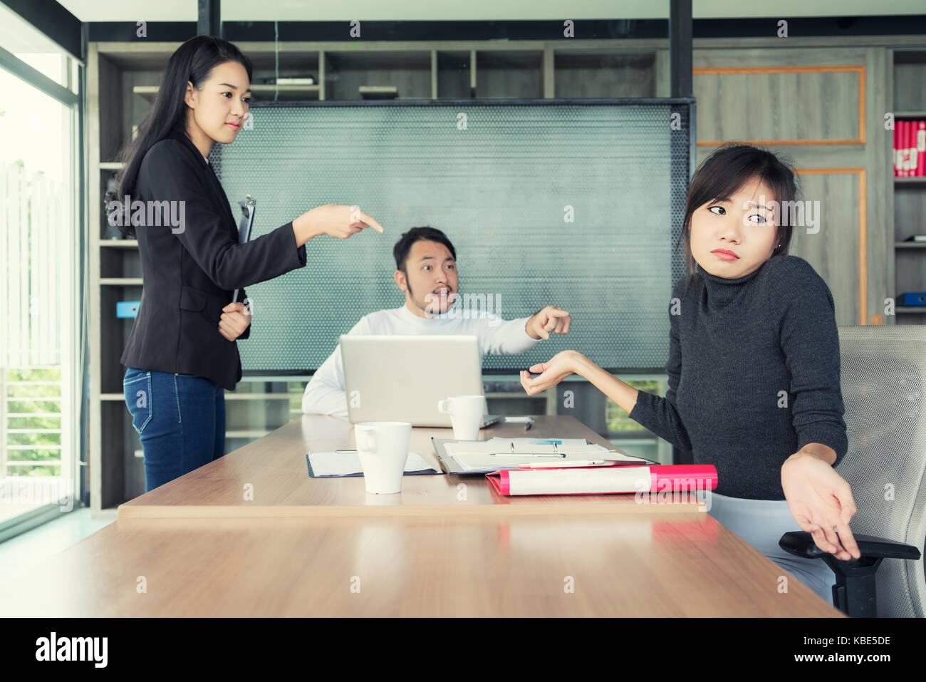 Group of Asian business people looking at businesswoman and blaming ...
