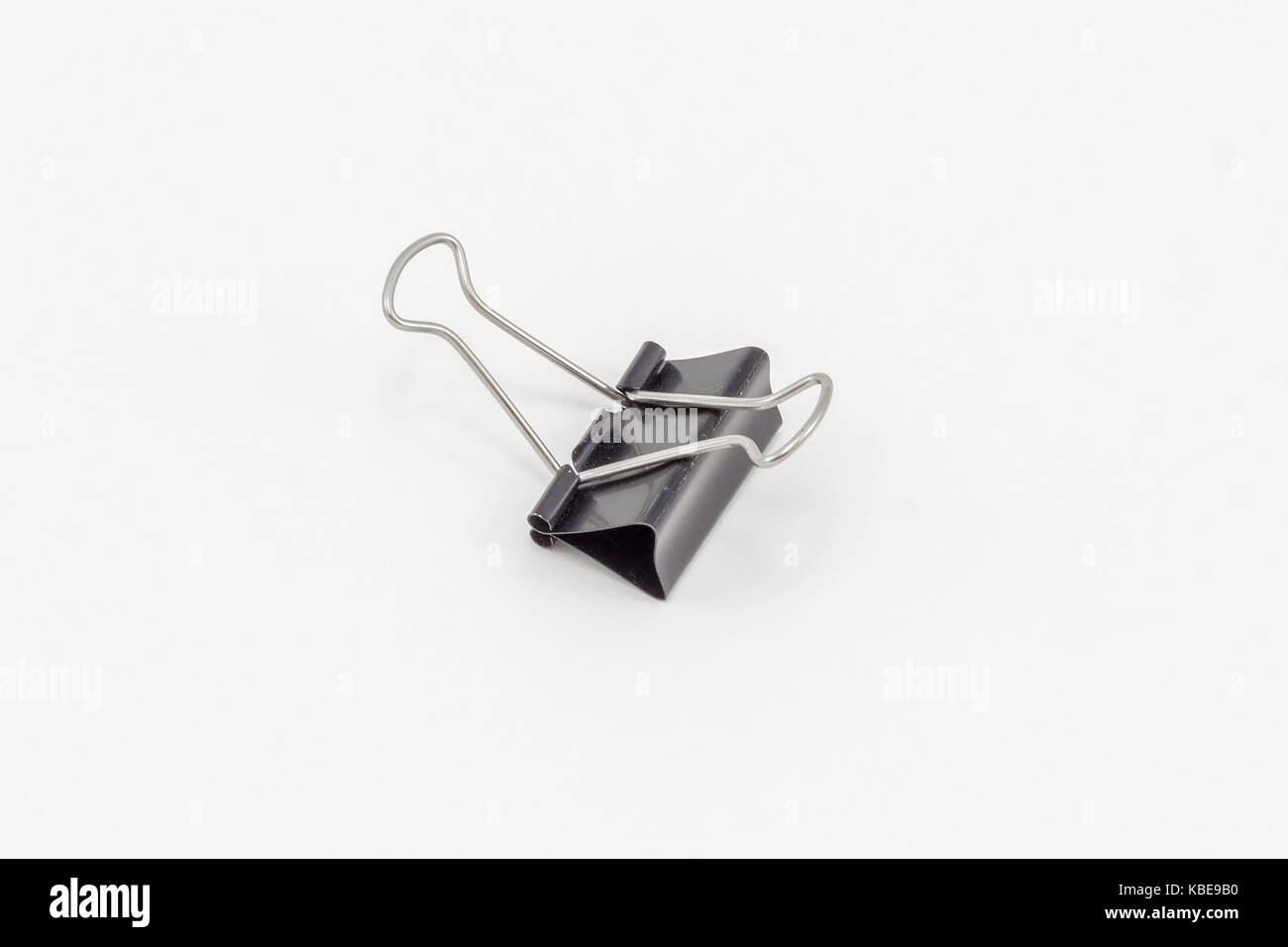 A binder clip, on it's side, on a white surface Stock Photo - Alamy