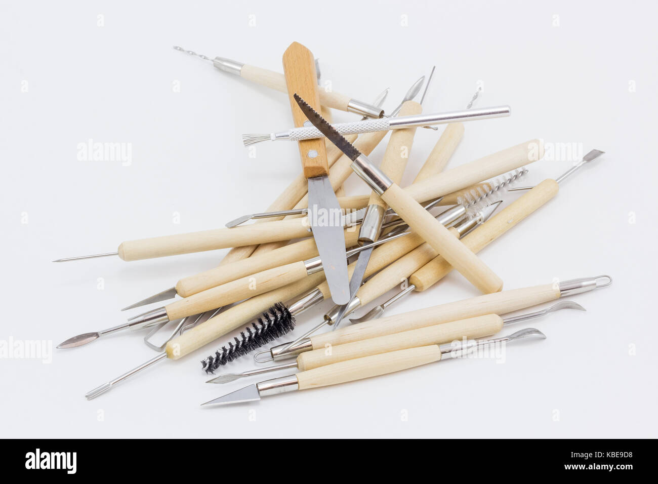 A pile of sculpture tools, made of wood and metal, on a white surface ...