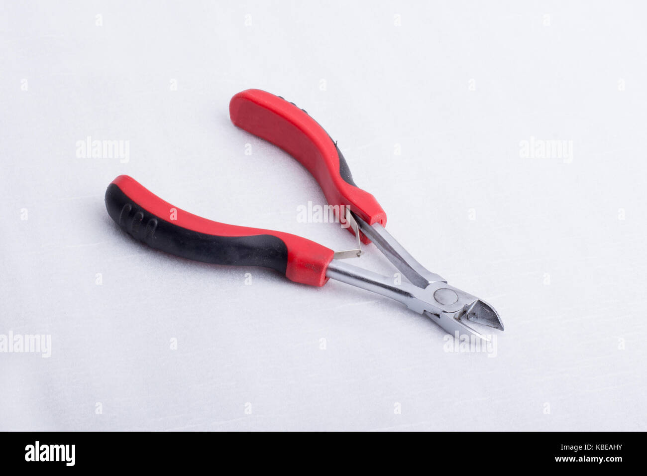 A wire cutter with a black and red handle on a white surface Stock ...
